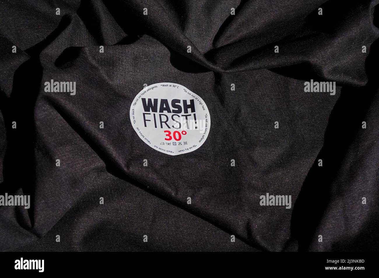 Sticker on a T-shirt with washing instructions and the text "Wash first ...