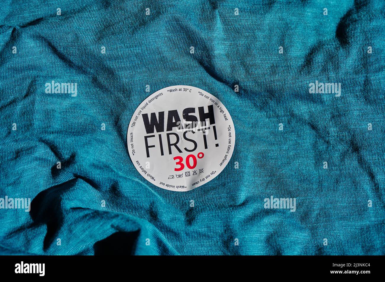 Sticker on a T-shirt with washing instructions and the text "Wash first ...