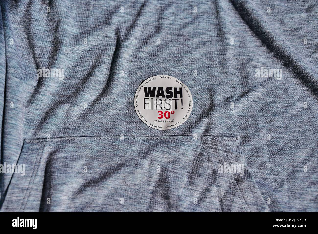 Sticker on a T-shirt with washing instructions and the text "Wash first ...