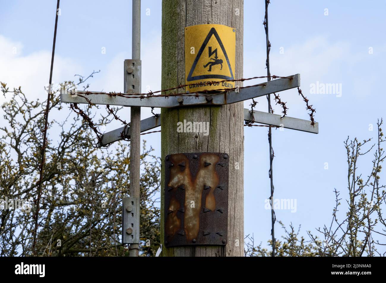 A Danger of Death warning sign mounted on a wooden pole above a metal ...