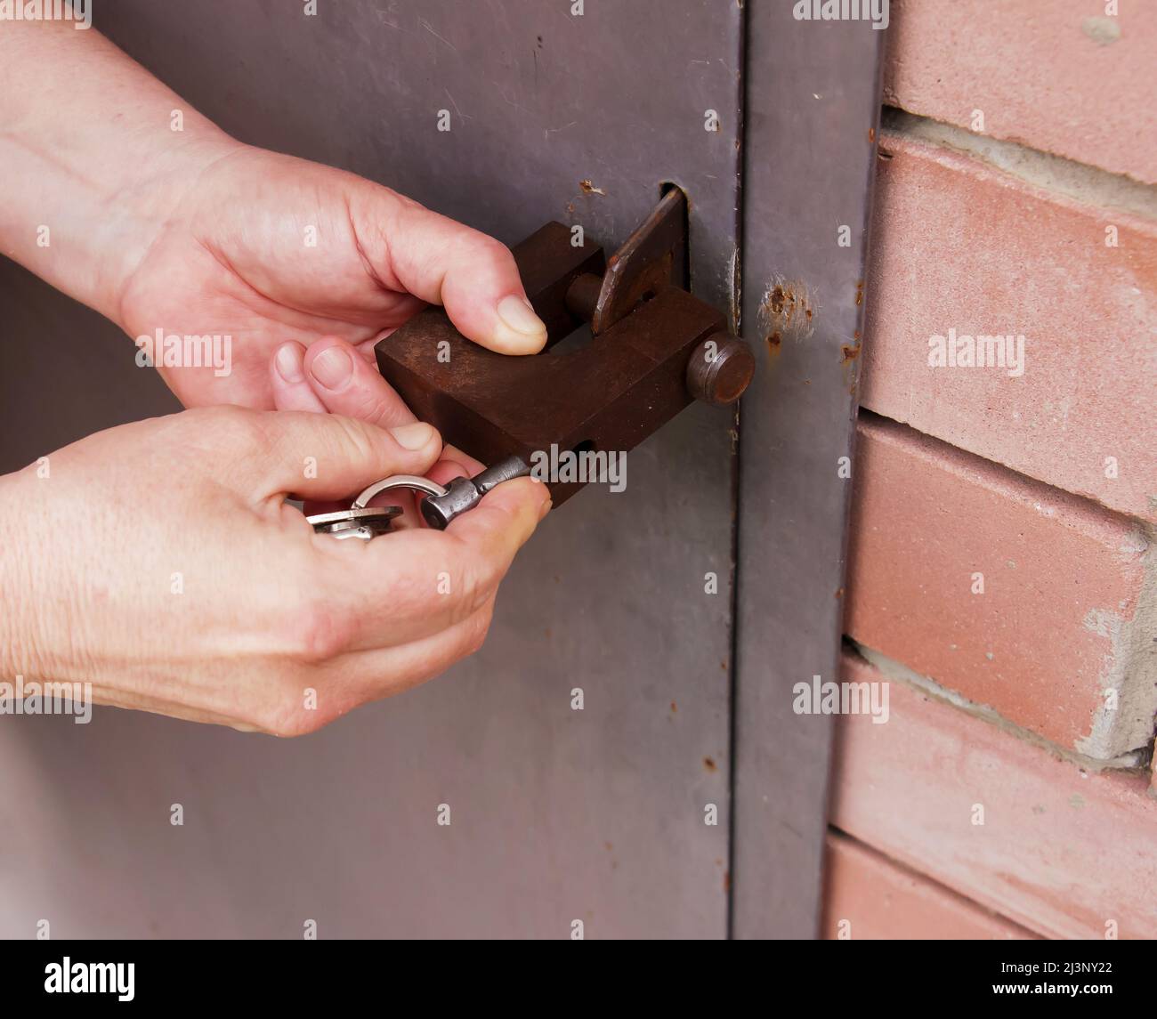 Women's hands open a rusty lock with keys. Lock on a metal door ...