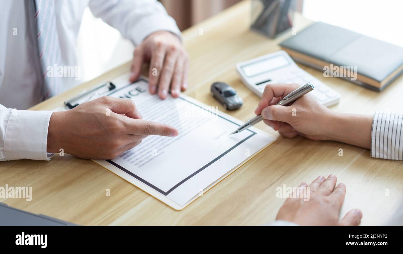 Insurance concept the male dealer suggesting his customer to sign the ...