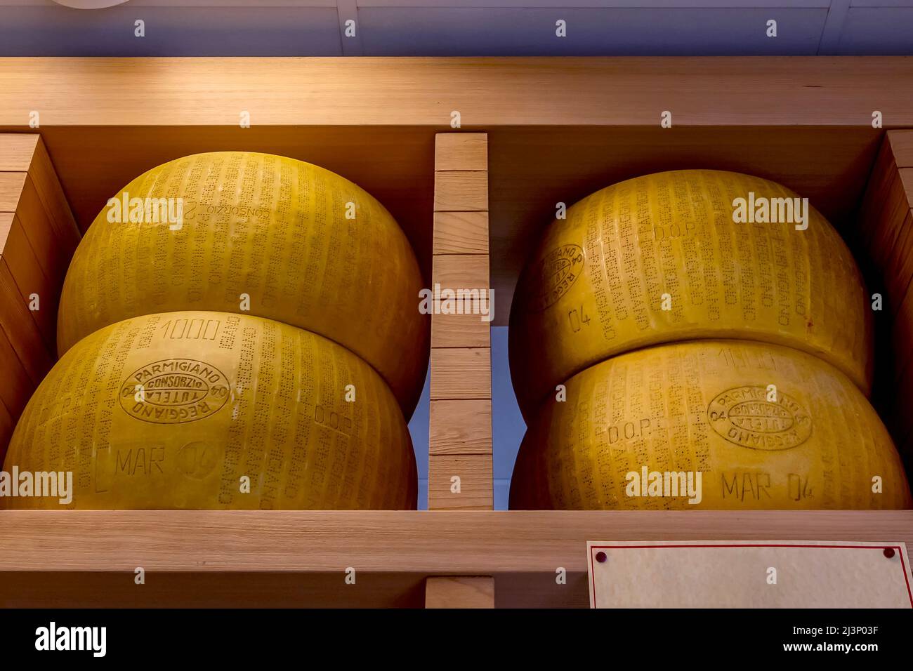 Four large wheels of Parmigiano Reggiano D.O.P. in a wooden shelving ...