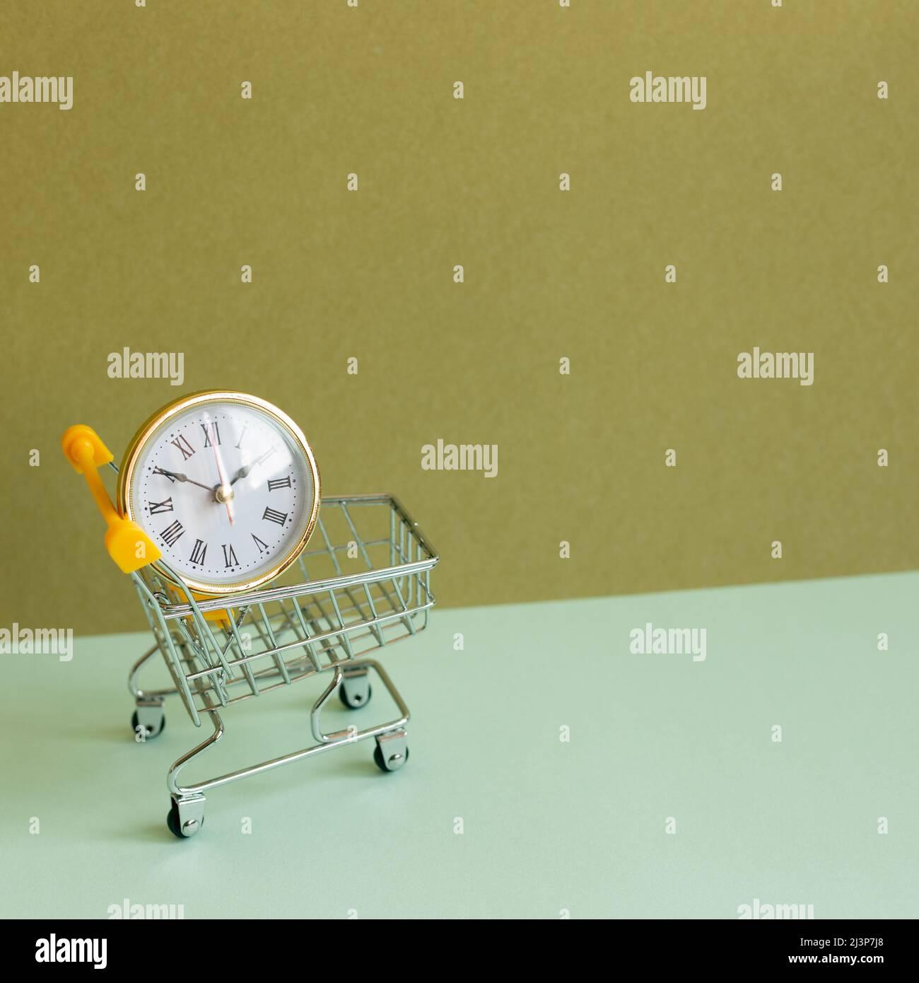 Clock in shopping cart on sky blue and khaki background Stock Photo - Alamy
