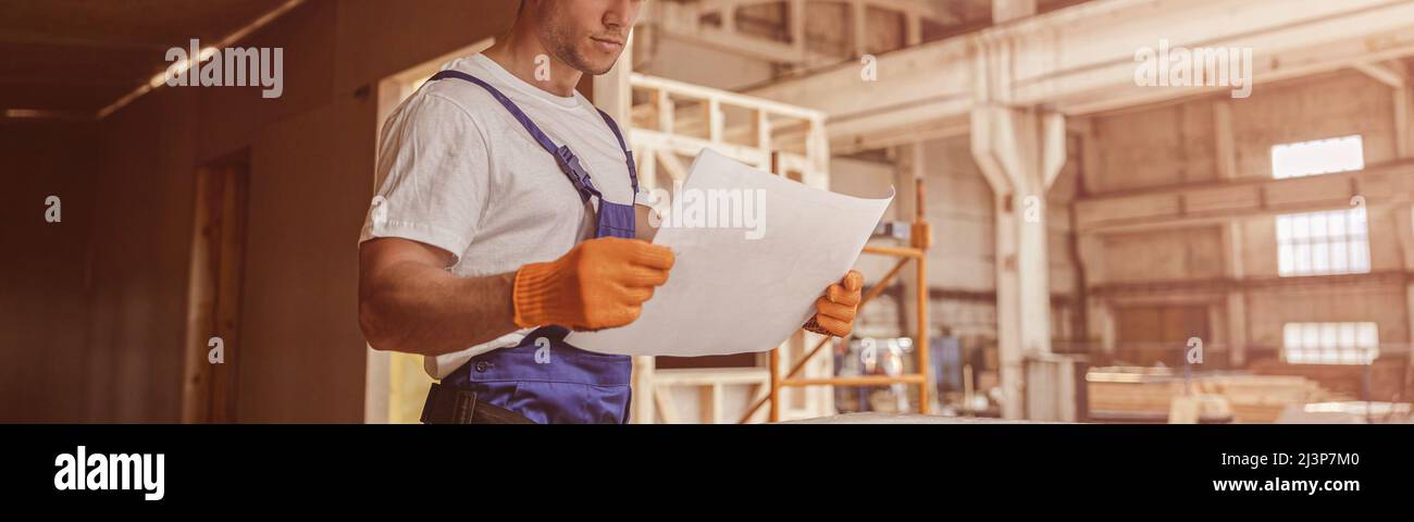 Serious man builder studying architectural plan at construction site ...