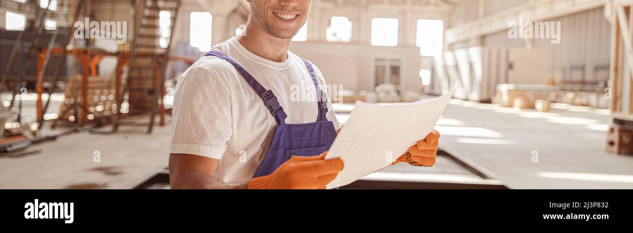 Cheerful male worker holding building architectural plan Stock Photo ...