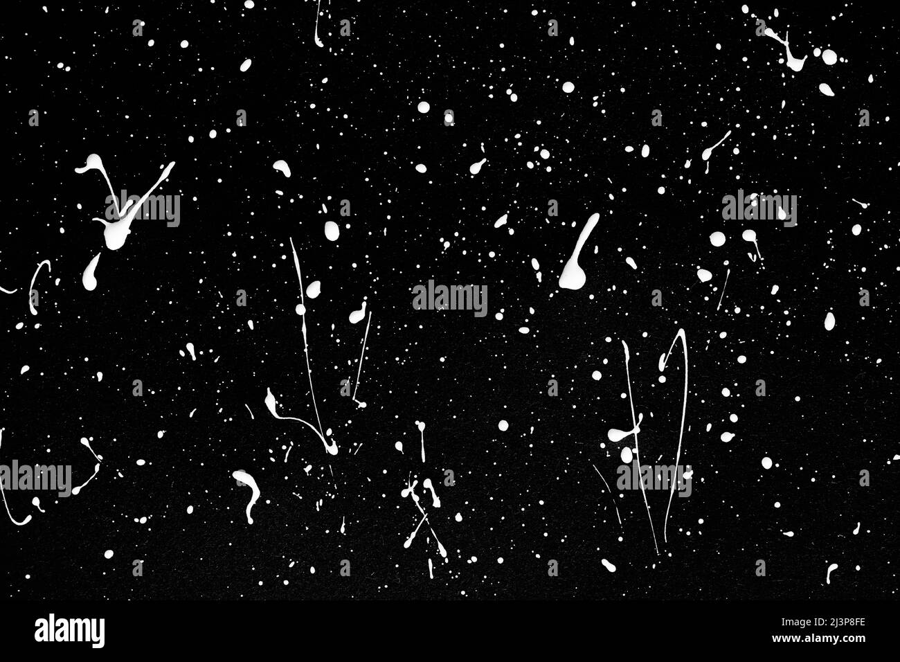 closeup of white paint drops on black paper background for design ...