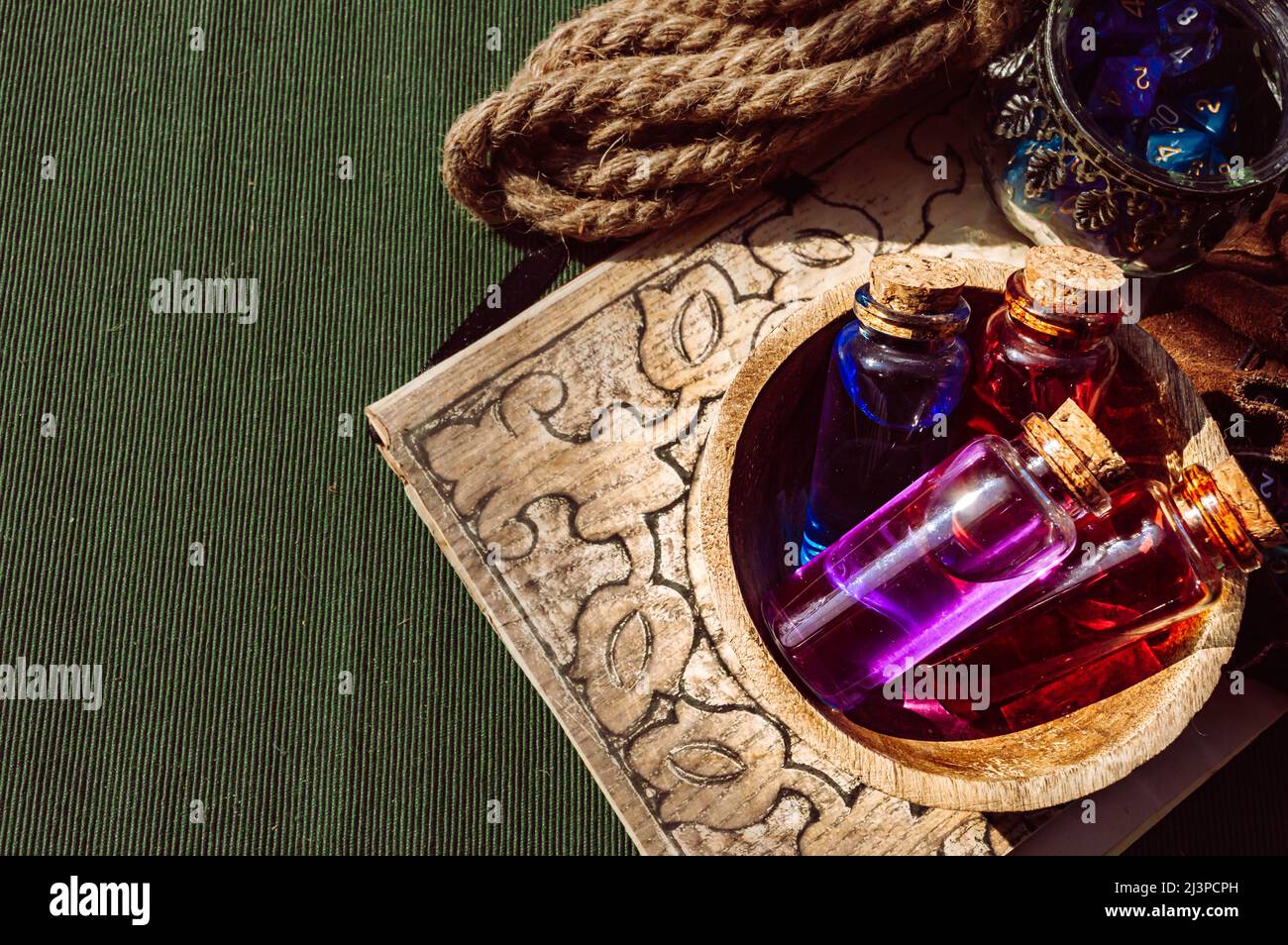 Overhead view of potions and multi-colored dice on an olive green ...