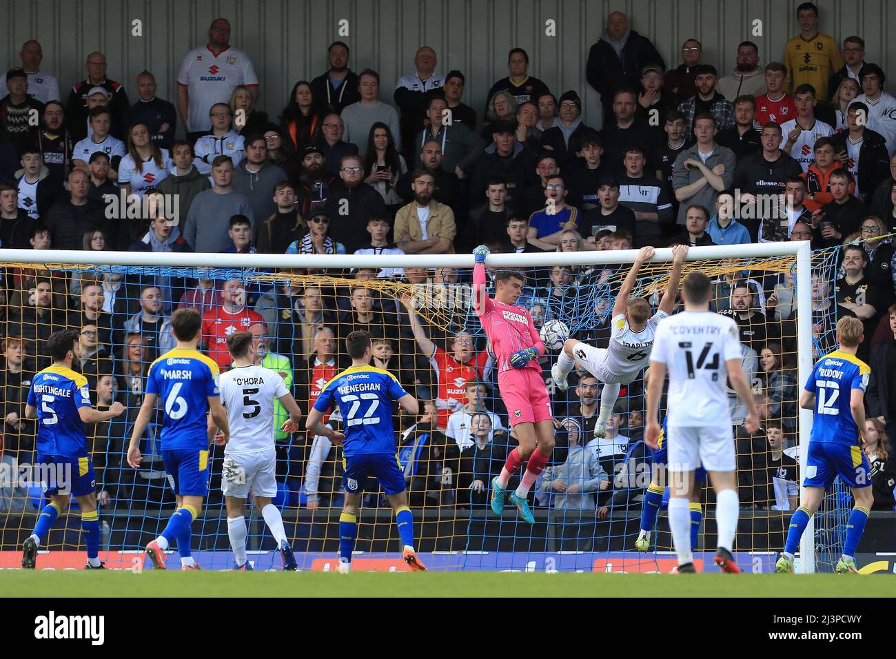 Nik Tzanev #1 of AFC Wimbledon sees a ball over the bar with Harry Darling #6 of Milton Keynes ...