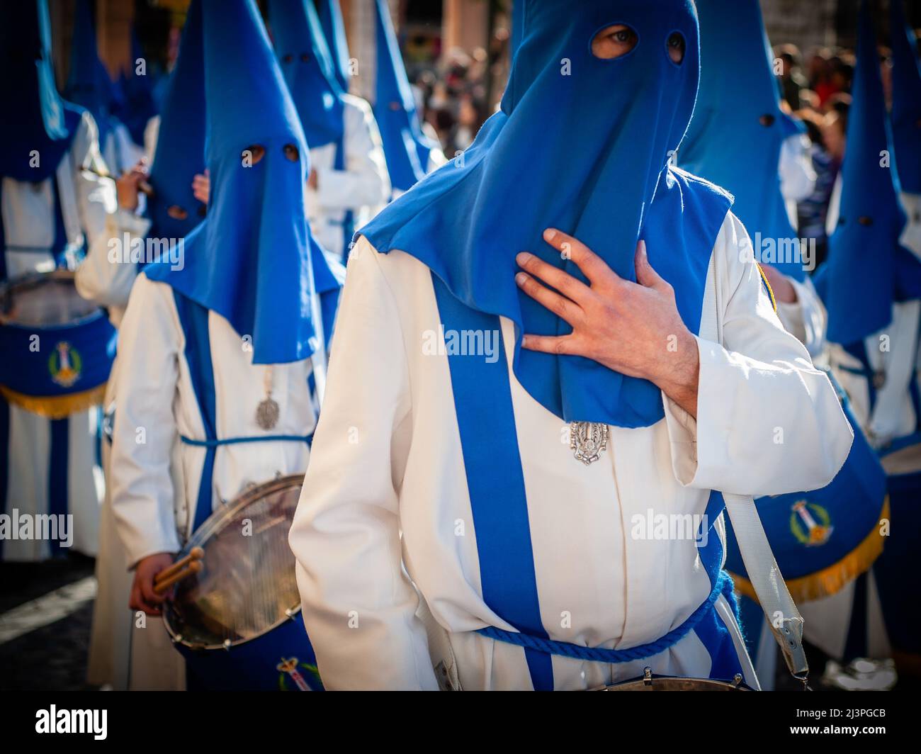 A man is seen wearing a blue capirote (a Catholic pointed hat of ...