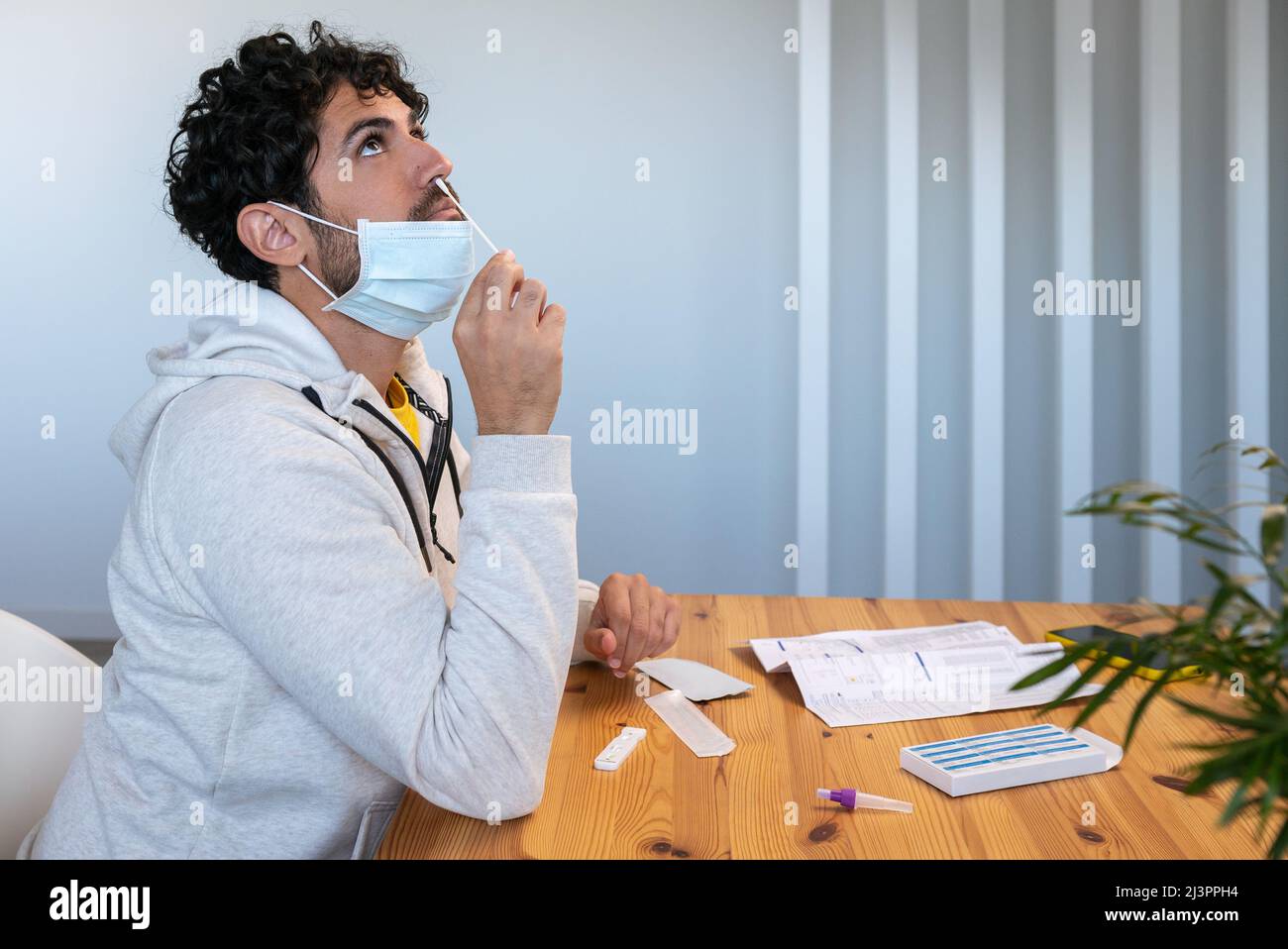 Portrait of relaxed man wearing mask and taking a self swabbing home ...
