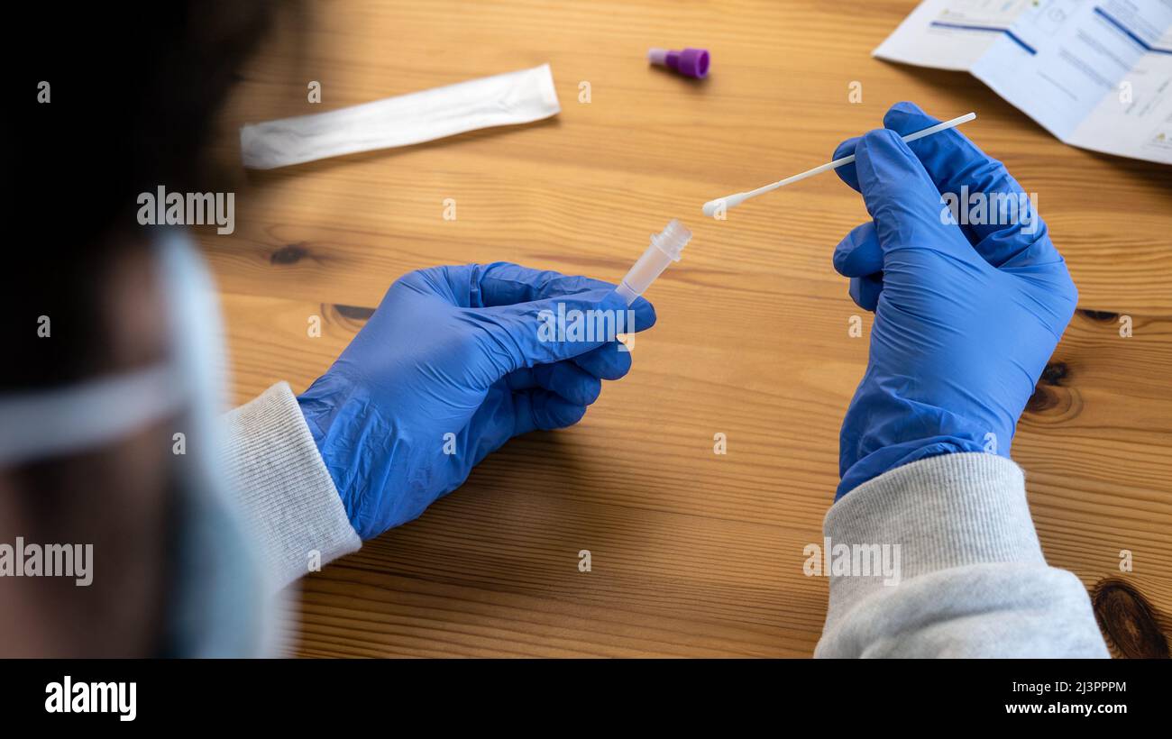 Close-up of man wearing latex gloves taking a self swabbing home tests ...