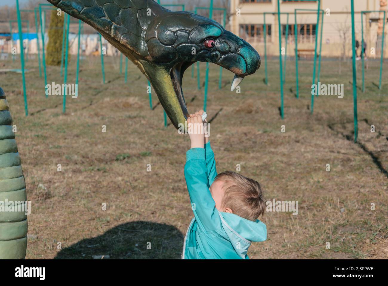 A little boy plays with a snake statue Stock Photo - Alamy