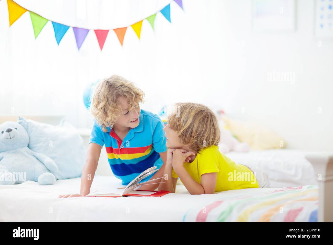 Child reading book in bed. Bedroom for two kids. Little boys read books ...