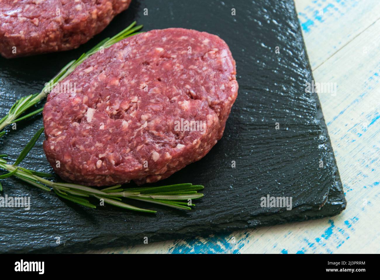 Two raw minced meat patties on a black stone surface Stock Photo - Alamy