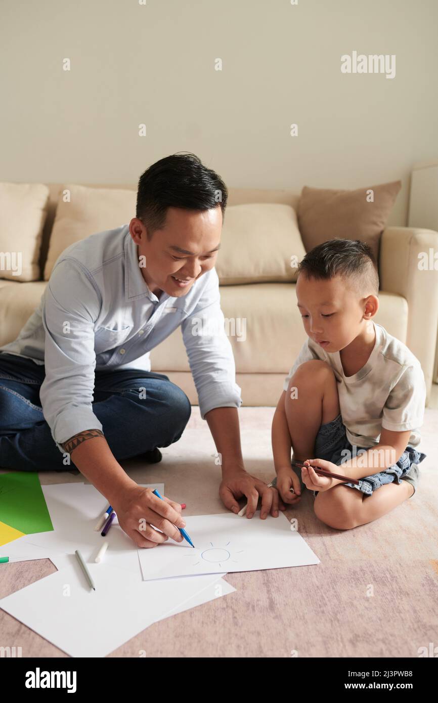 Happy father enjoying helping little son with drawing picture for ...