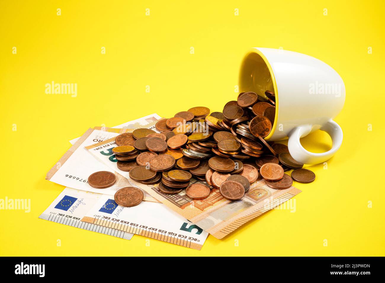 the coins spilled from a coffee cup between some Euro banknotes Stock ...