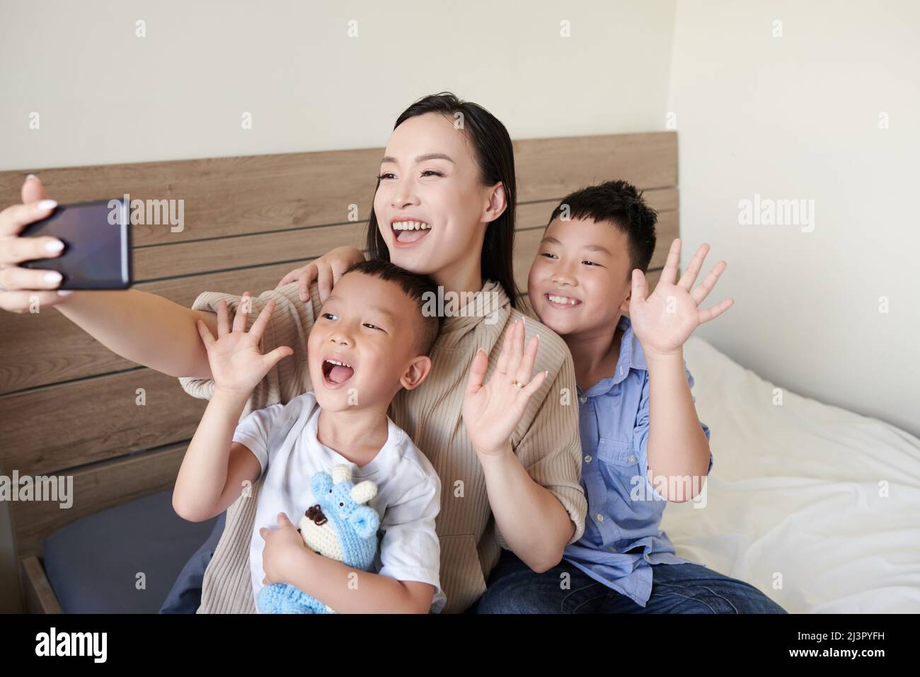 Happy excited mother and her two sons waving with hands when video ...