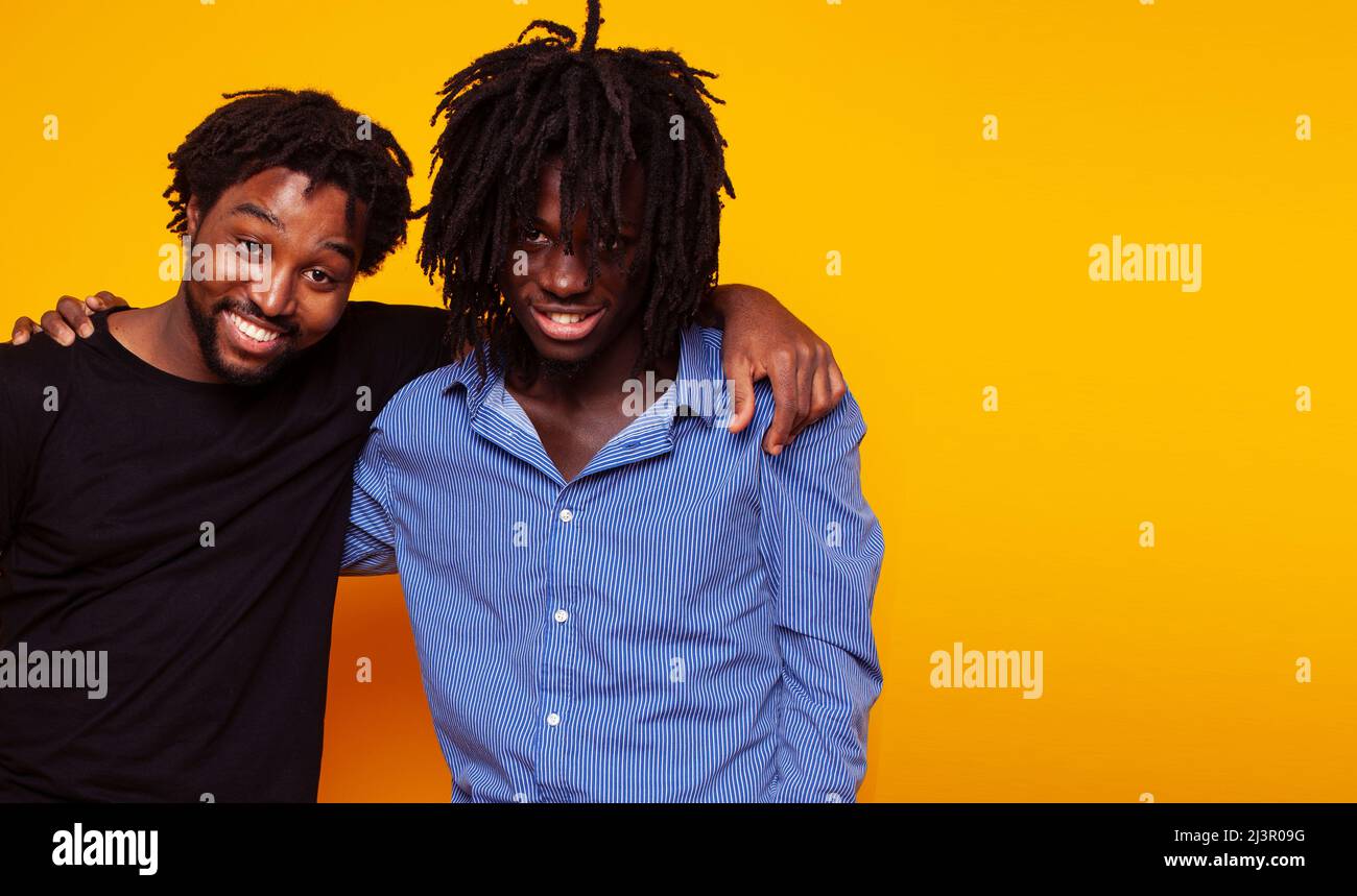 two african american guys posing cheerful together on yellow background ...