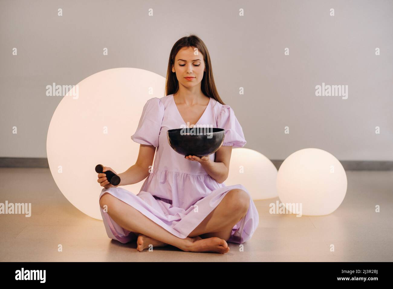 Portrait of a female yoga teacher playing a Tibetan bowl or singing a ...