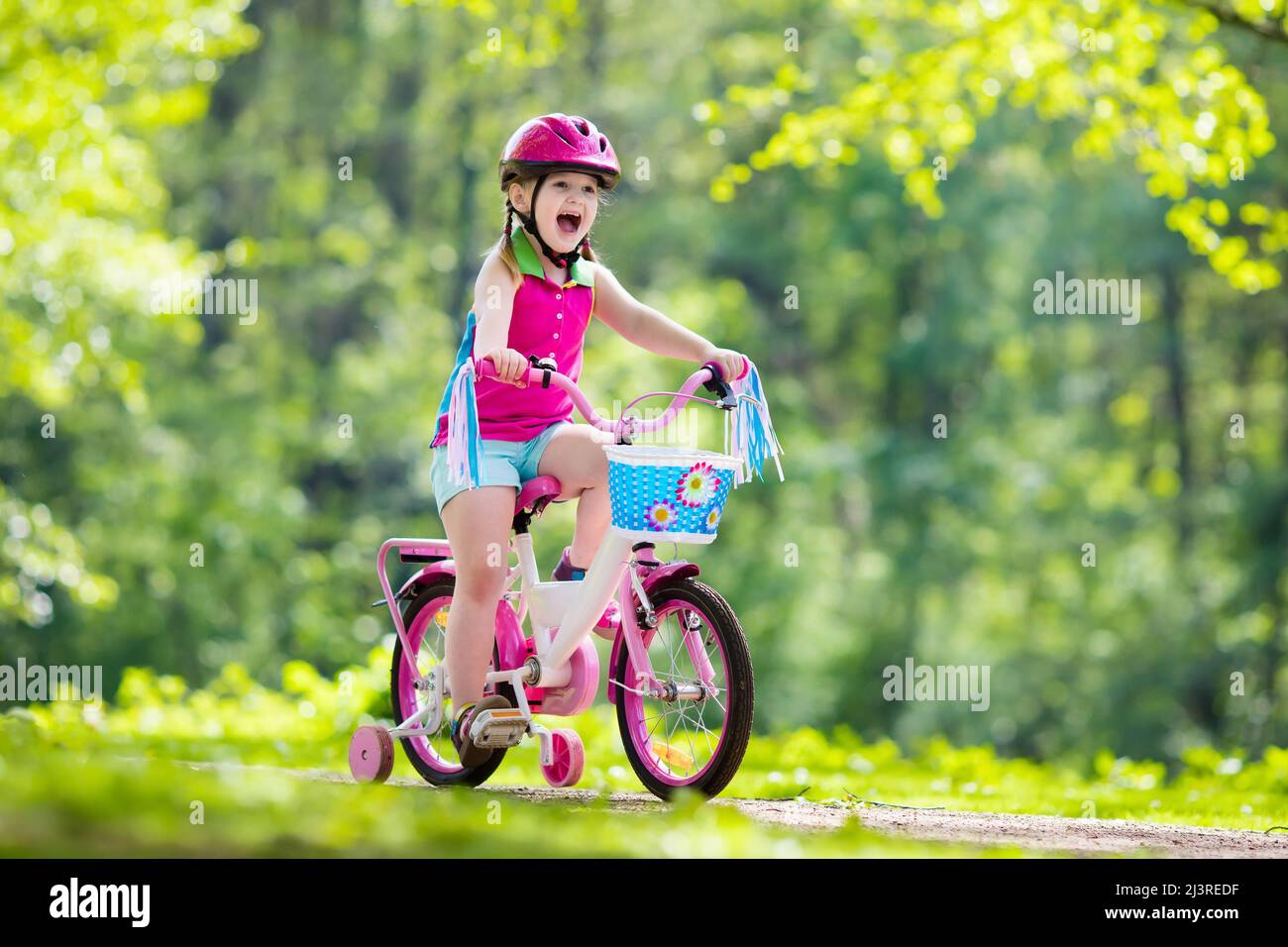 Child riding bike. Kid on bicycle in sunny park. Little girl enjoying ...