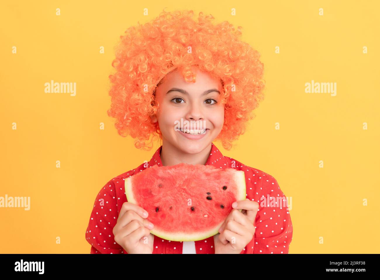 cheerful kid in fancy orange hair wig holding fresh ripe water melon ...