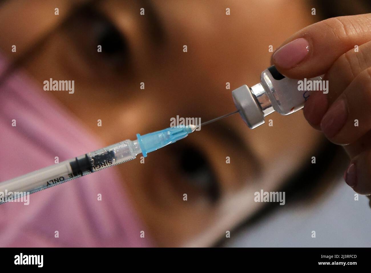 London, UK. 9th Apr, 2022. A doctor draws the first dose of the Pfizer ...