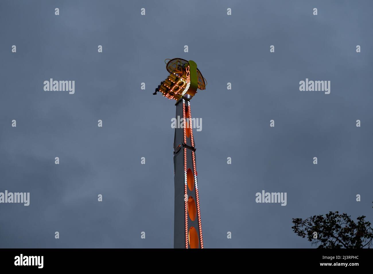 Fairground ride very high in the air in front of a dark sky. Colorful ...
