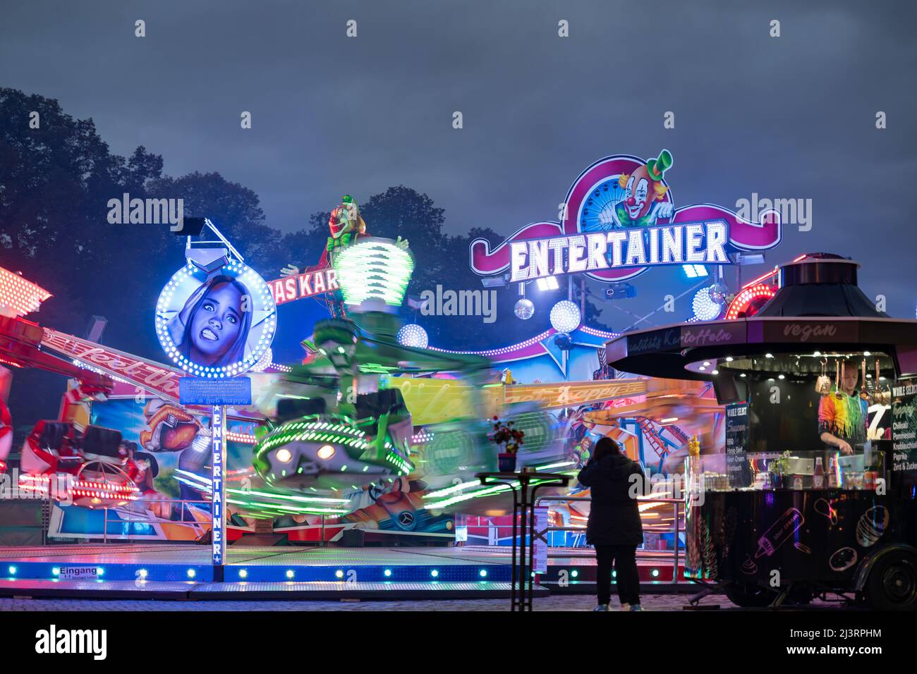 Entertainer funfair ride with a big illuminated logo in the evening ...