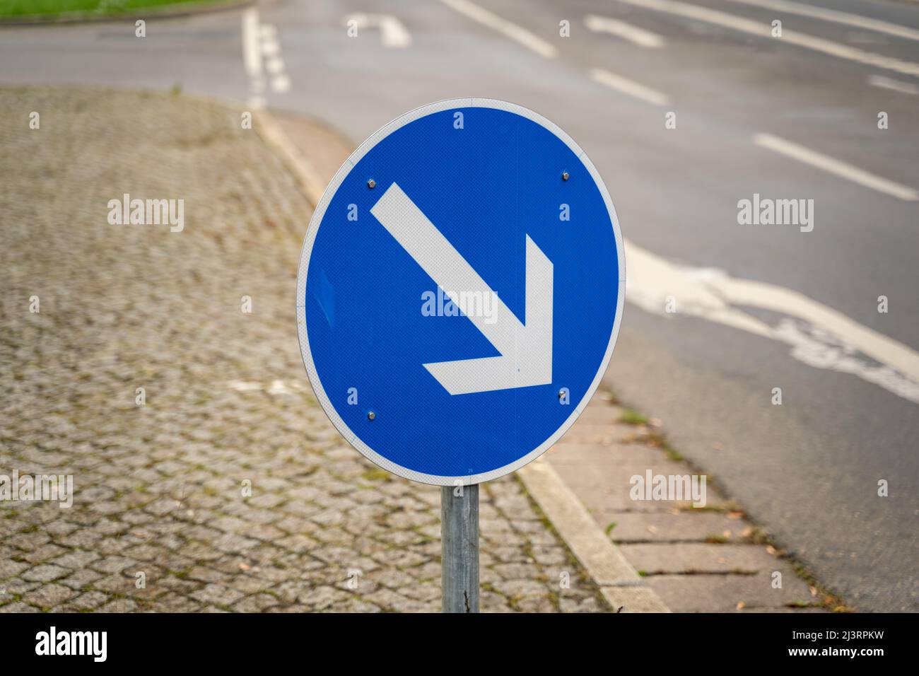 Keep right traffic sign next to an intersection in a German city. Close ...
