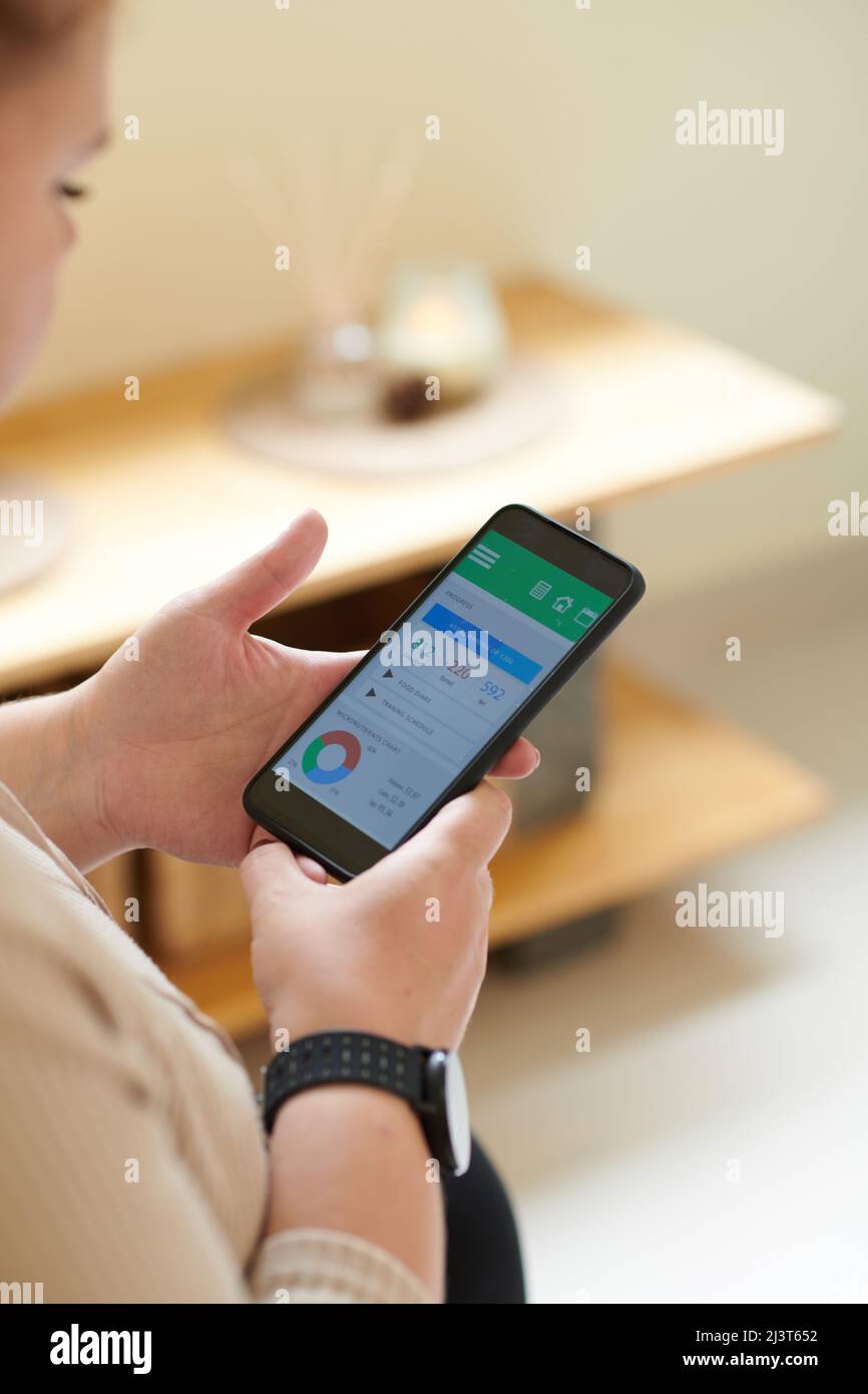Woman checking food diary and micronutrient chart in health application ...