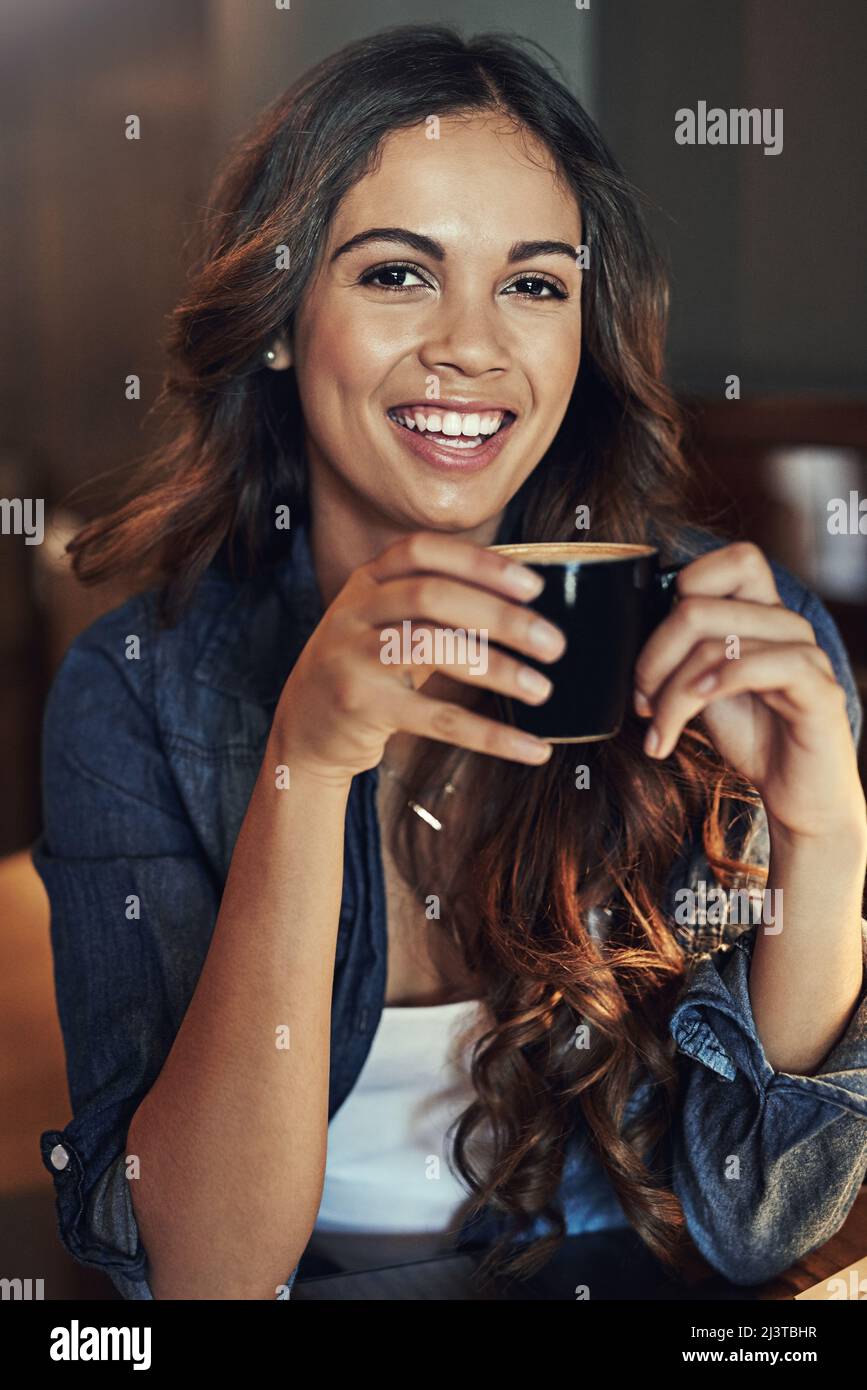 Oh look, its coffee o clock. Portrait of a relaxed young woman enjoying ...