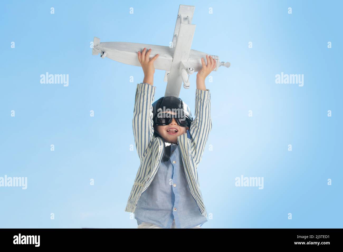 Child pilot with toy airplane dreams of traveling in summer in nature ...
