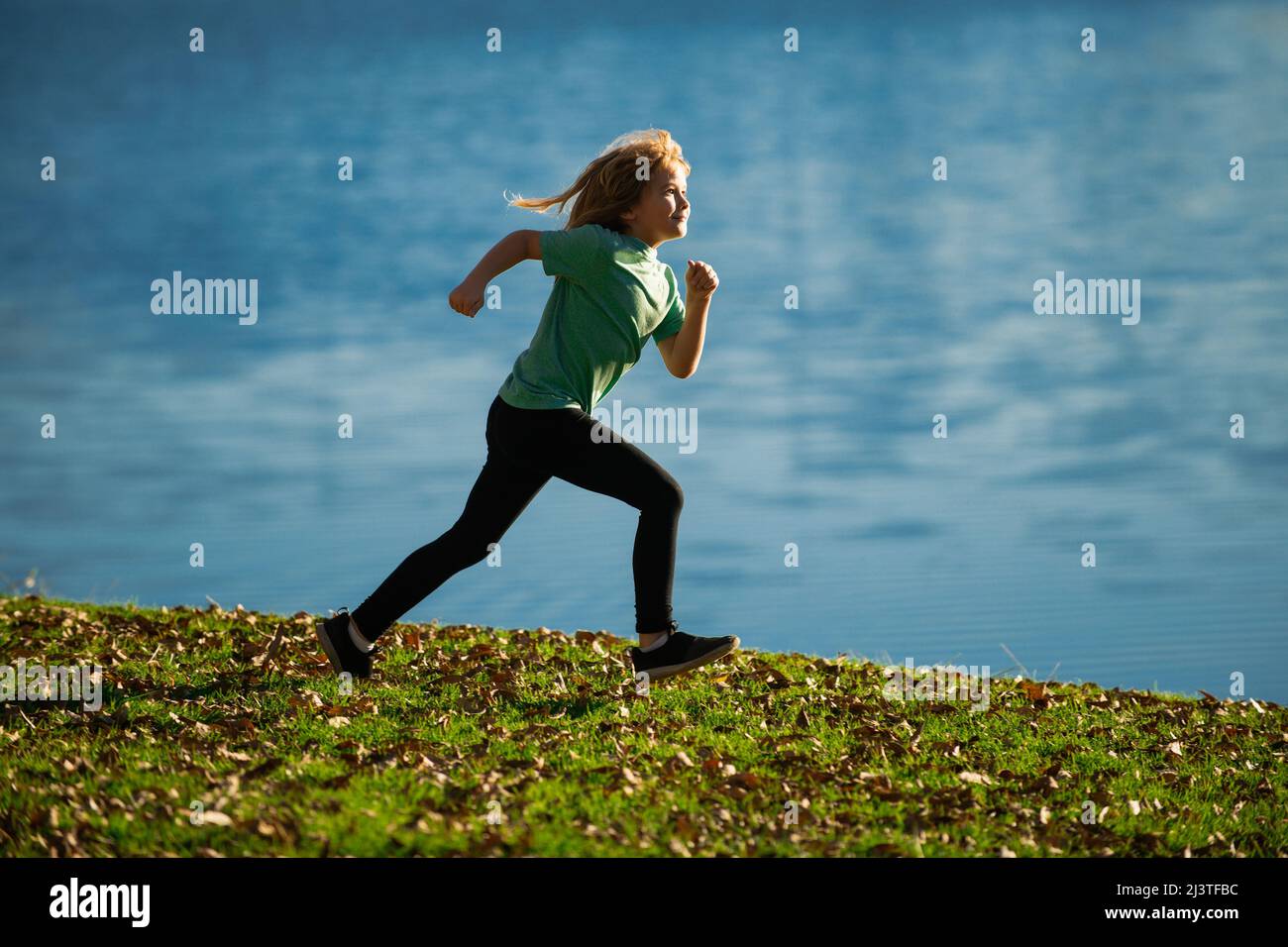Child running through water close to shore along the lake. Sporty young ...