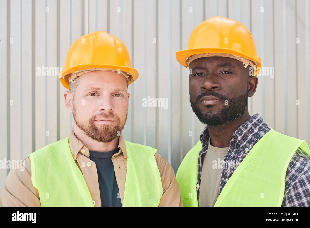 Portrait of two construction workers discussing project while standing ...