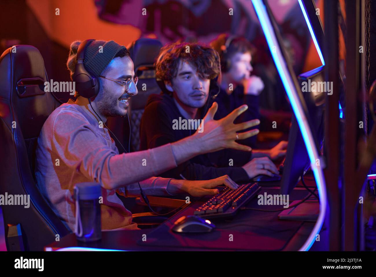 Positive young multi-ethnic guys in headsets sitting in front of ...