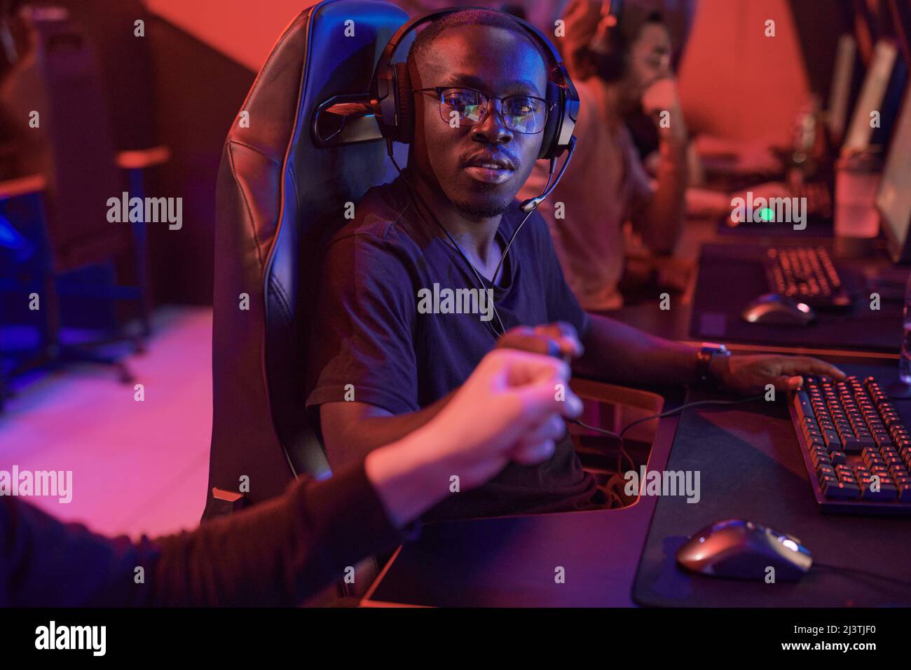 African-American gamer in headphones making fist bump with team member ...