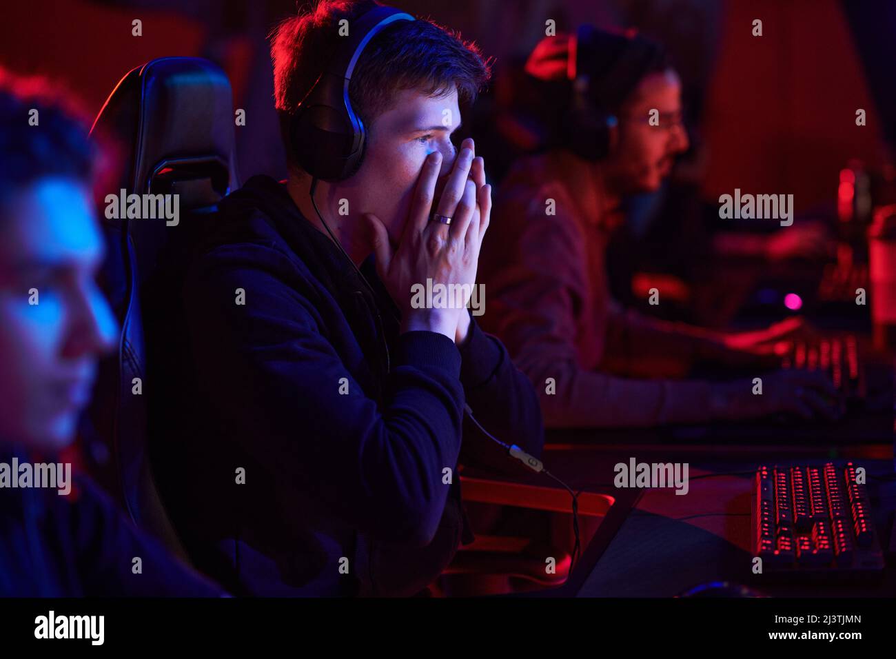 Shocked teenage gamer in headphones covering mouth and looking at ...