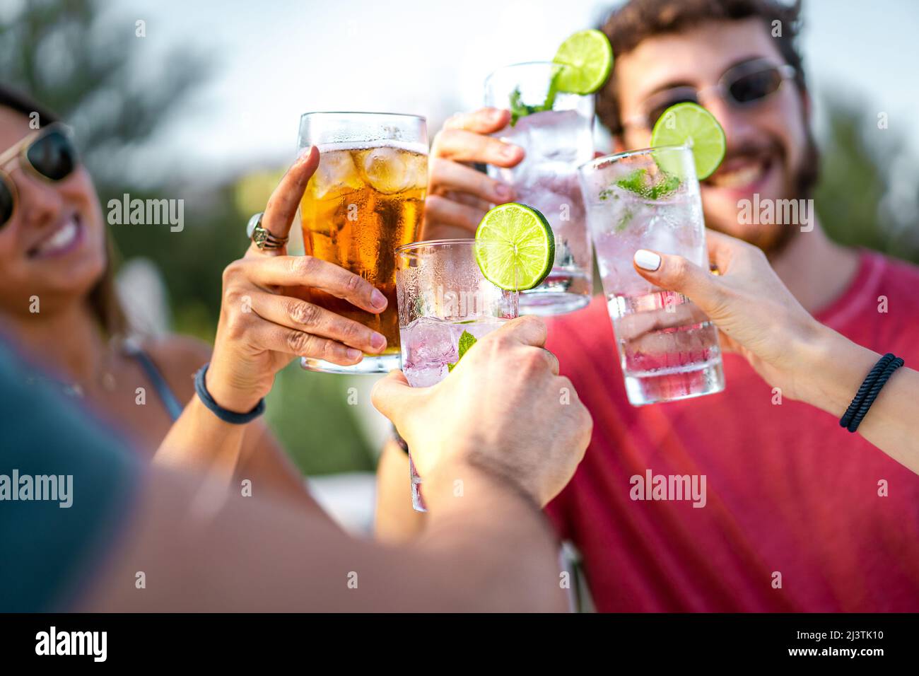 Happy young friends toasting with mojito cocktails together. Focus on ...