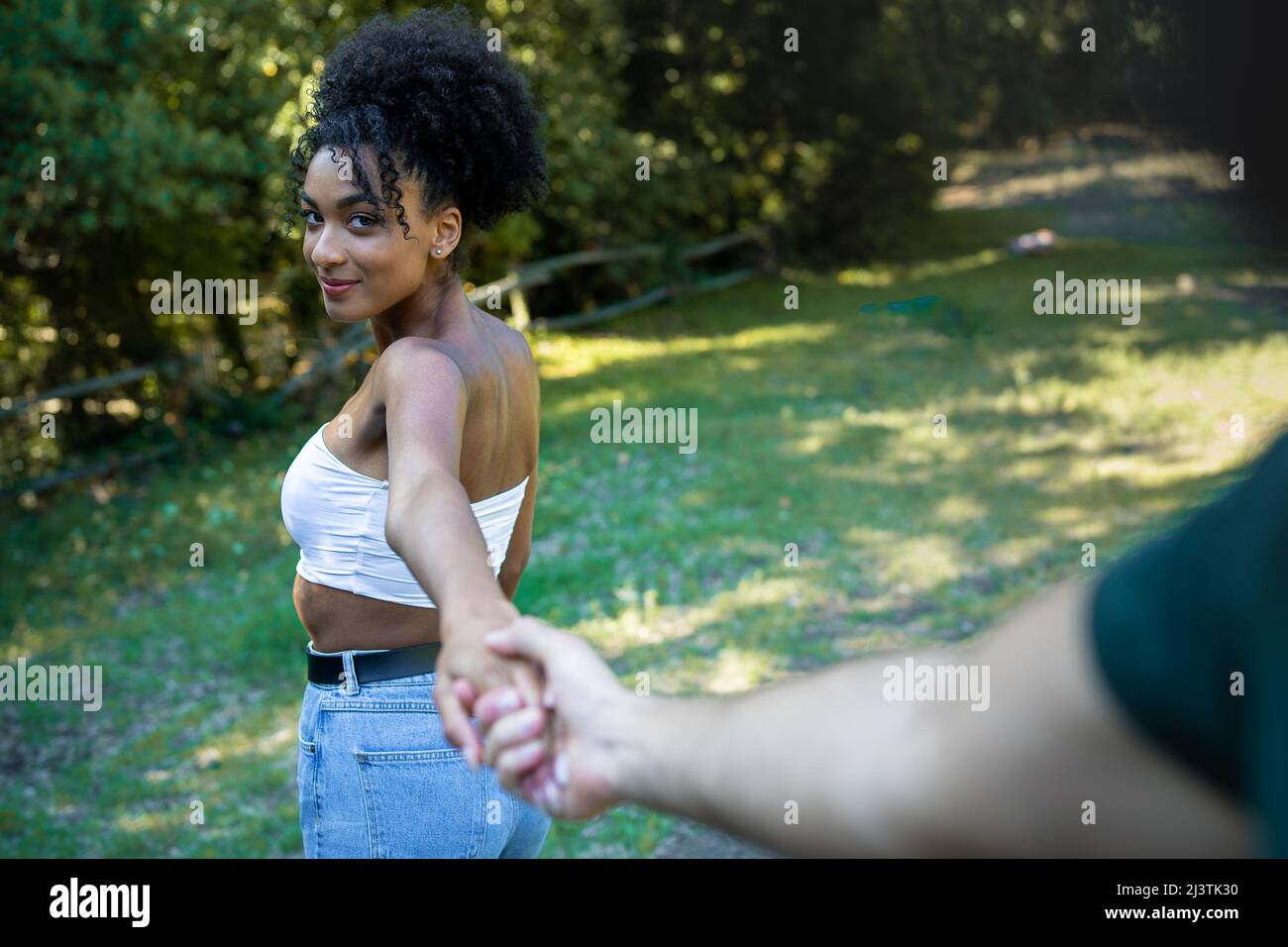 Beautiful African American girl holding caucasian mans hand and leading ...