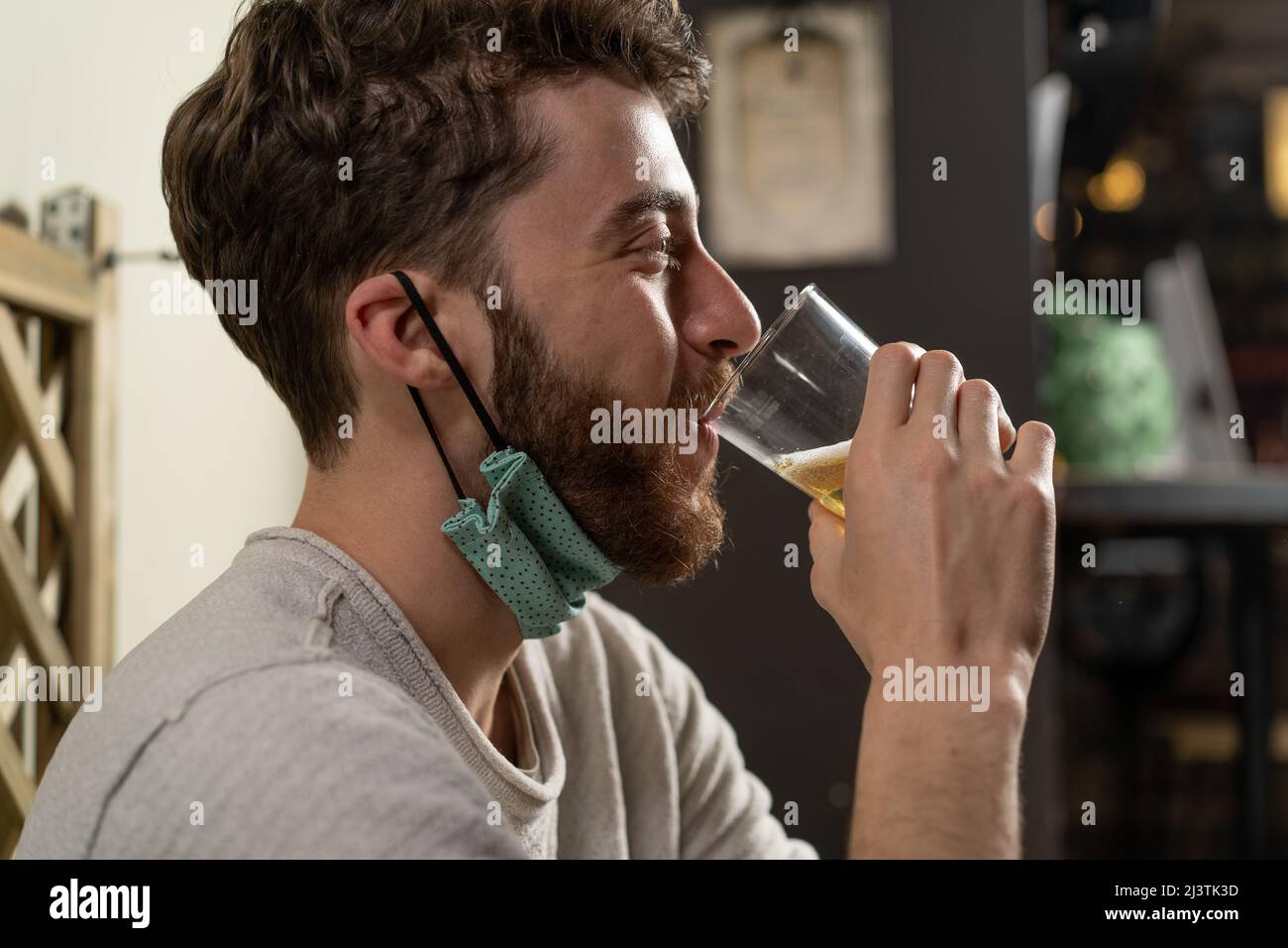 Handsome guy drinking lager beer from the glass sitting in a pub ...