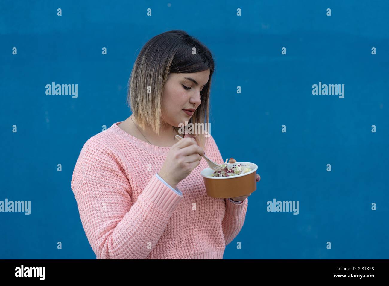 Cute curvy woman eating salad outdoors using plastic free organic ...