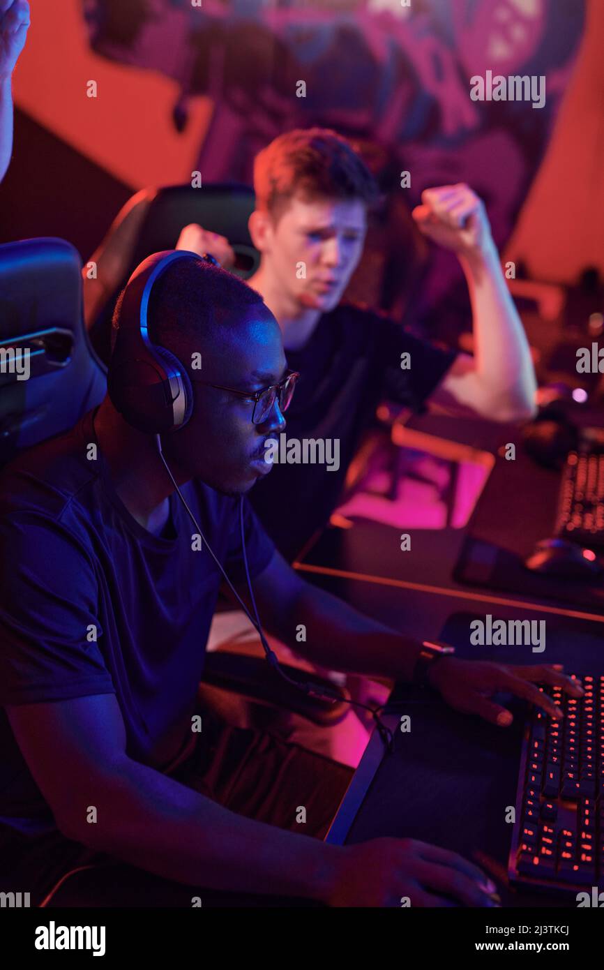 Young man making yes gesture while cheering for esports team member ...