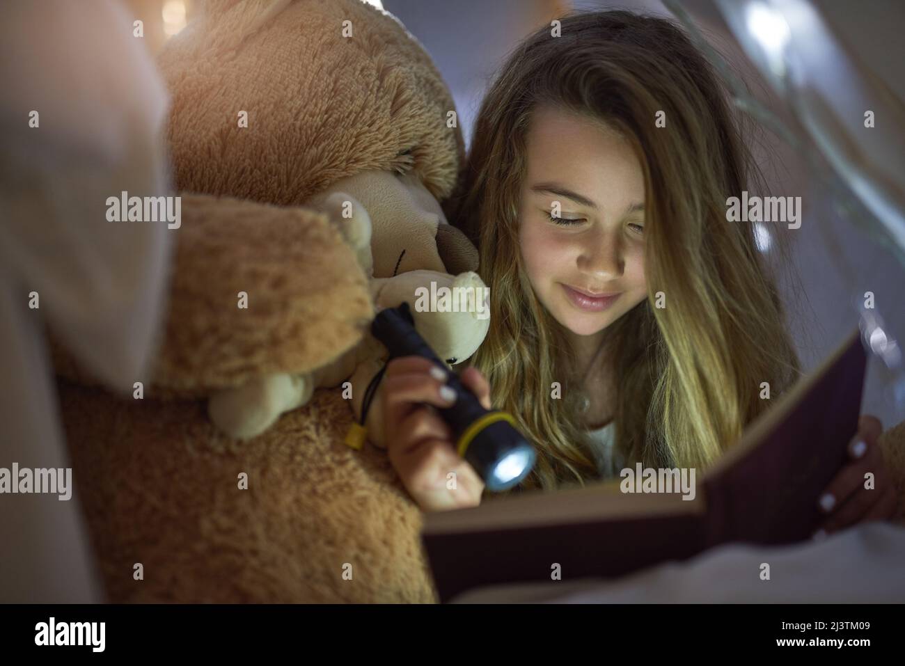 Getting stuck in a good story. Cropped shot of a young girl reading a ...