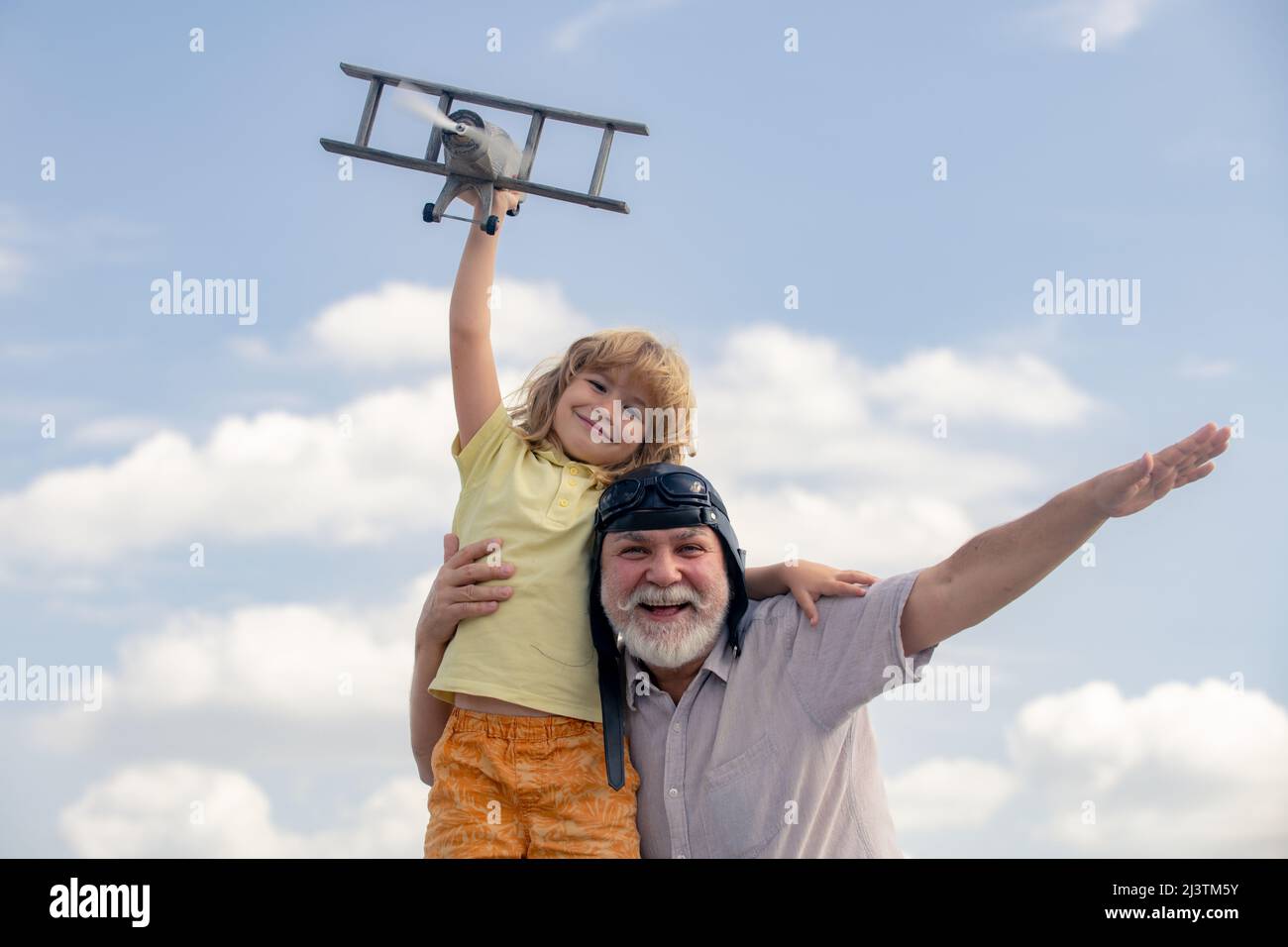 Grandfather and son playing with toy airplane against summer sky ...