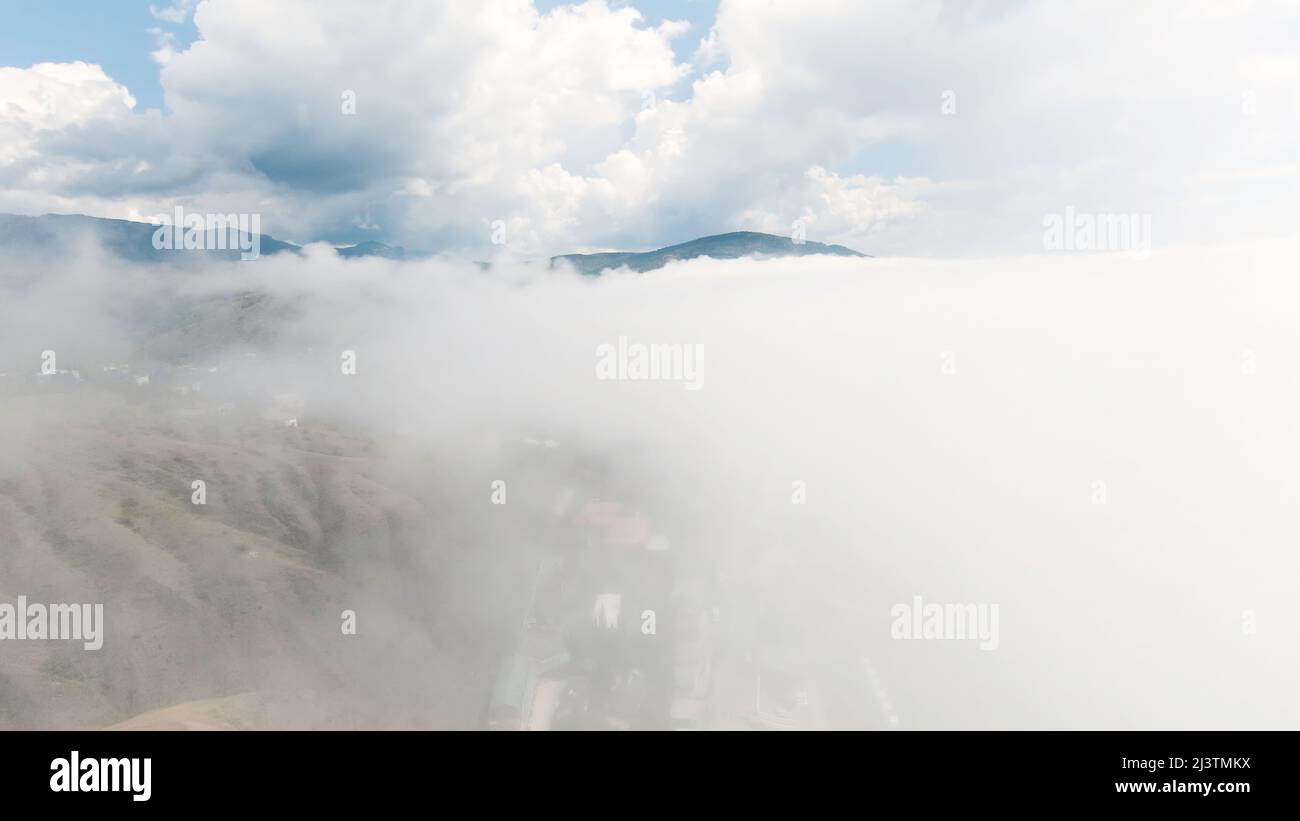 Top view of dense clouds in sky with mountain peaks. Action. Flying ...