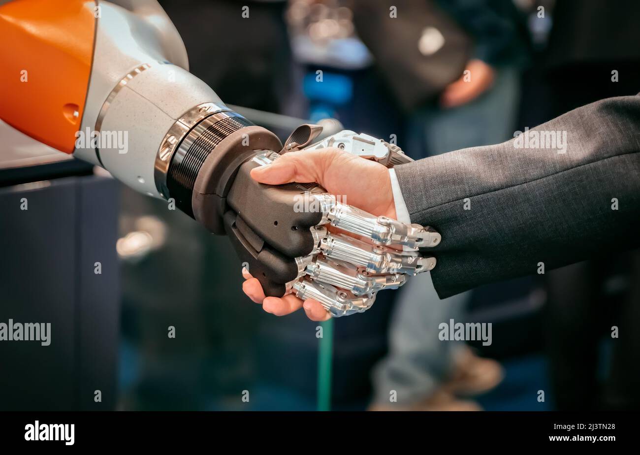 Hand of a businessman shaking hands with a Android robot. The concept ...