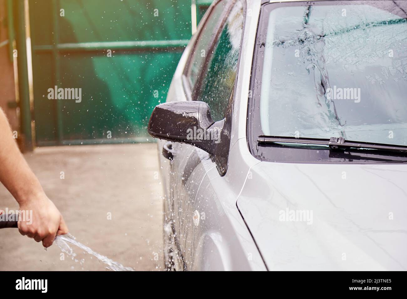 Man washing the car with water with the hose in the private yard ...