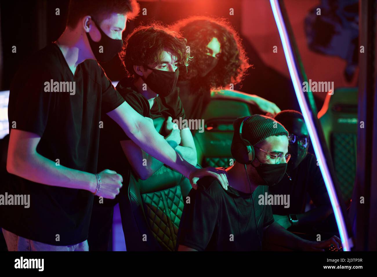 Group of young men in cloth masks supporting gamer participating in ...