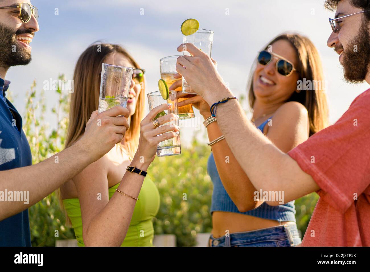 Friends toast at outdoors party. Young people toasting with cocktails ...
